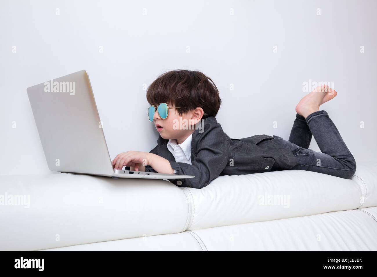 Asian Chinese little boy playing laptop on the couch in the living room ...