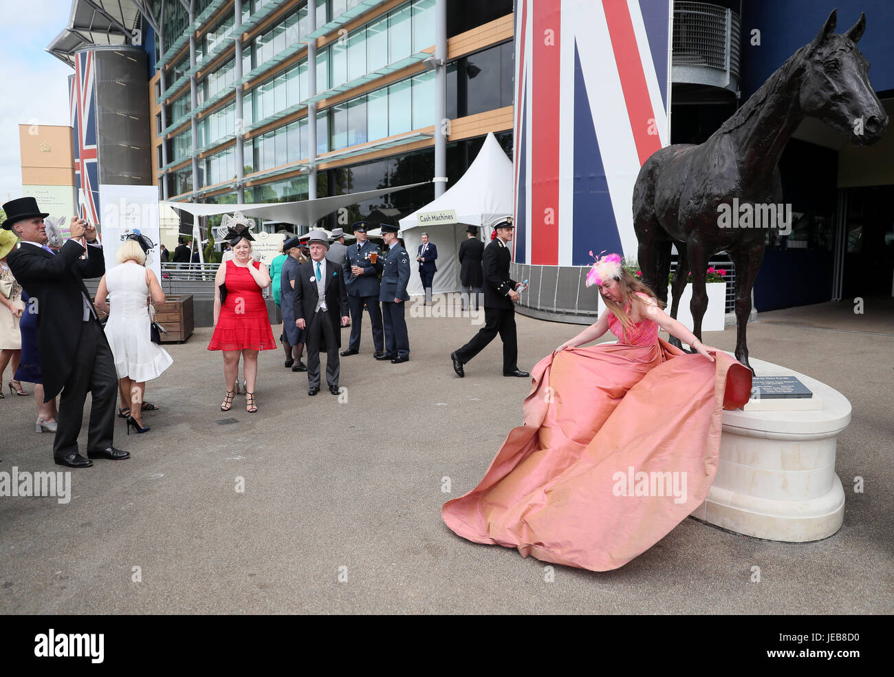 A racegoer struggles with her dress in the windy conditions by the ...
