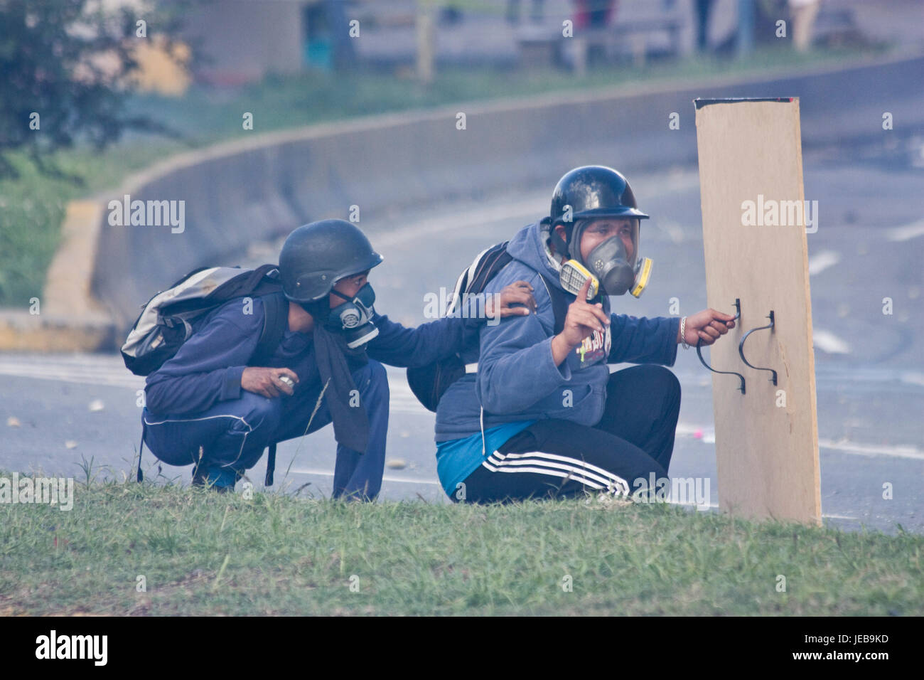 Two demonstrators hide behind a home made shield during a clash with ...