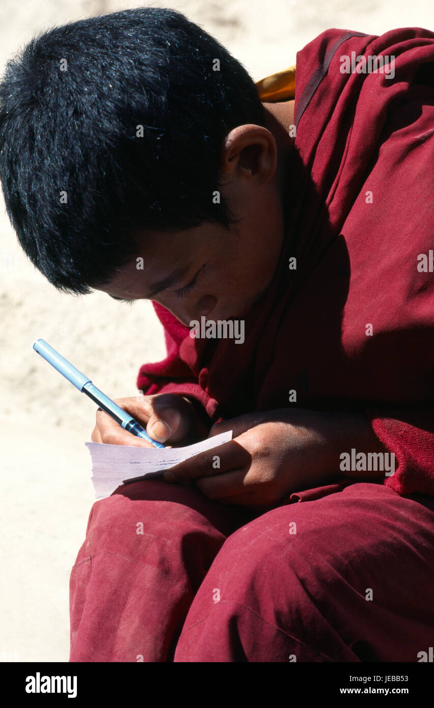 India, Ladakh, Tikse, Close up of a novice monk writing with a pen and ...