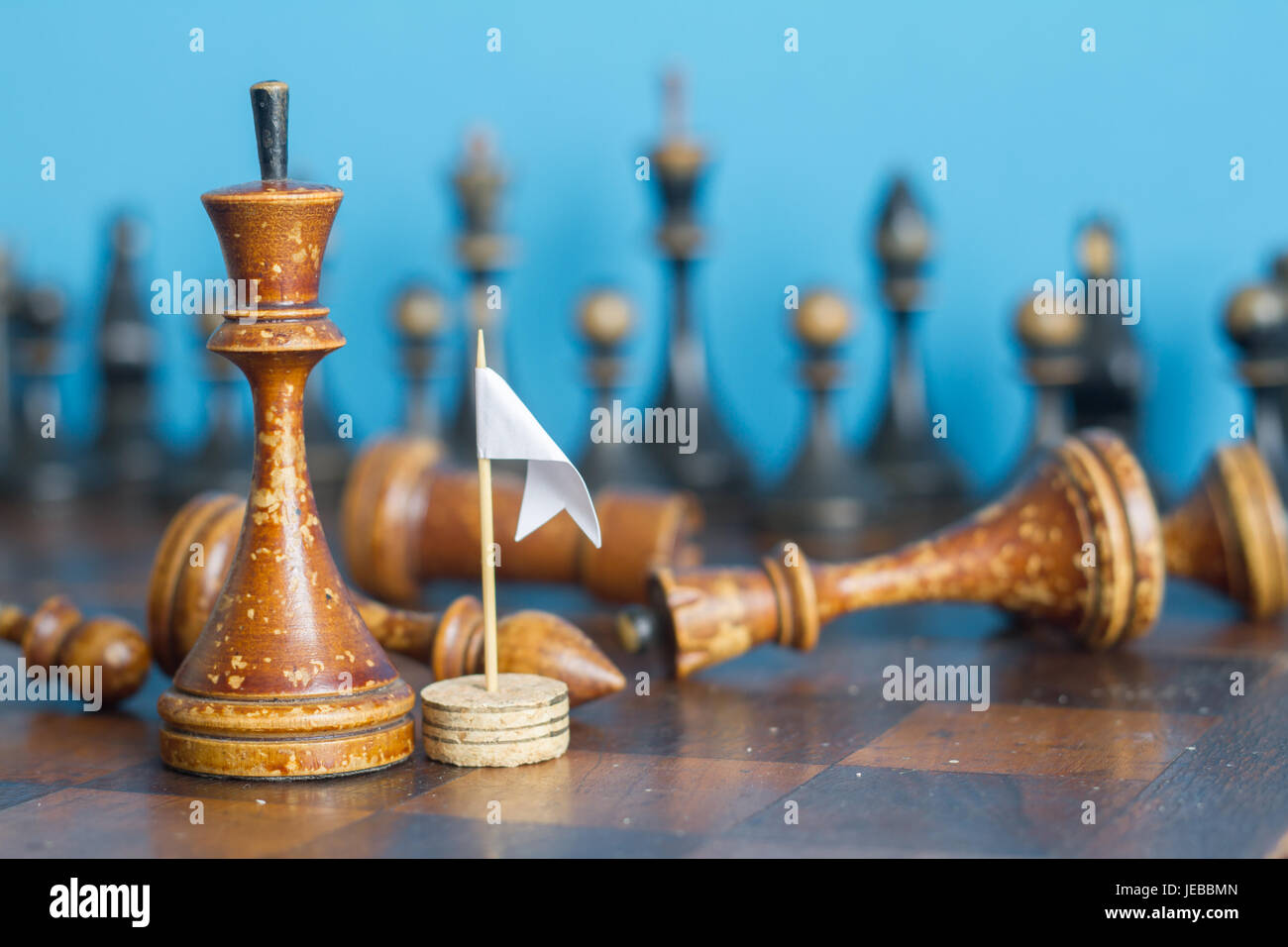 Ancient wooden chess pieces on an old chessboard. With the white flag ...