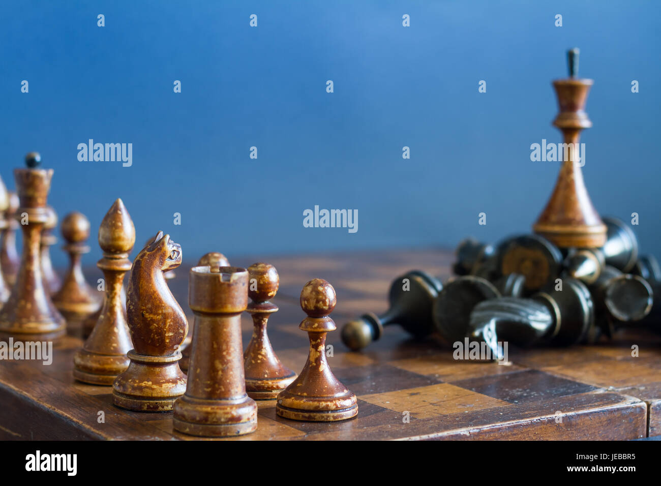 Ancient wooden chess pieces on an old chessboard. On a blue background ...