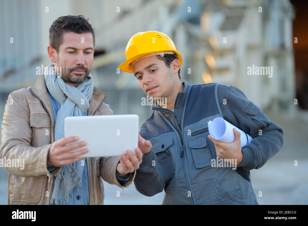 constructor and manager working on modern tablet outside renovated ...