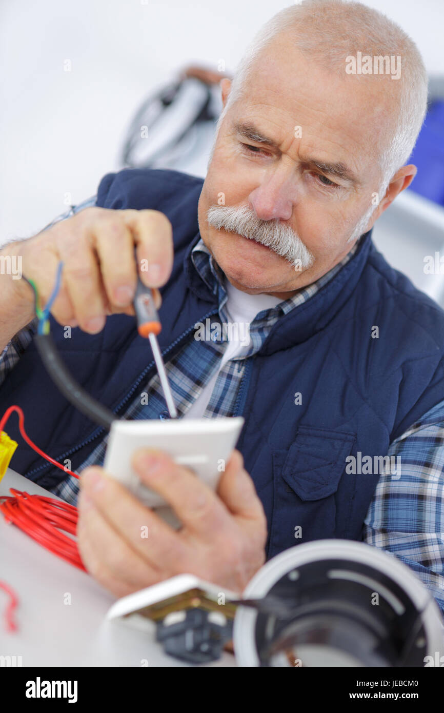 man repairing cellphone with screwdriver on desk Stock Photo - Alamy