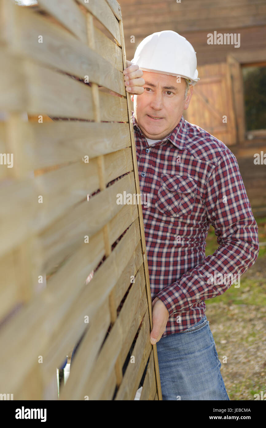 senior construction worker carrying a framed interior wall Stock Photo ...