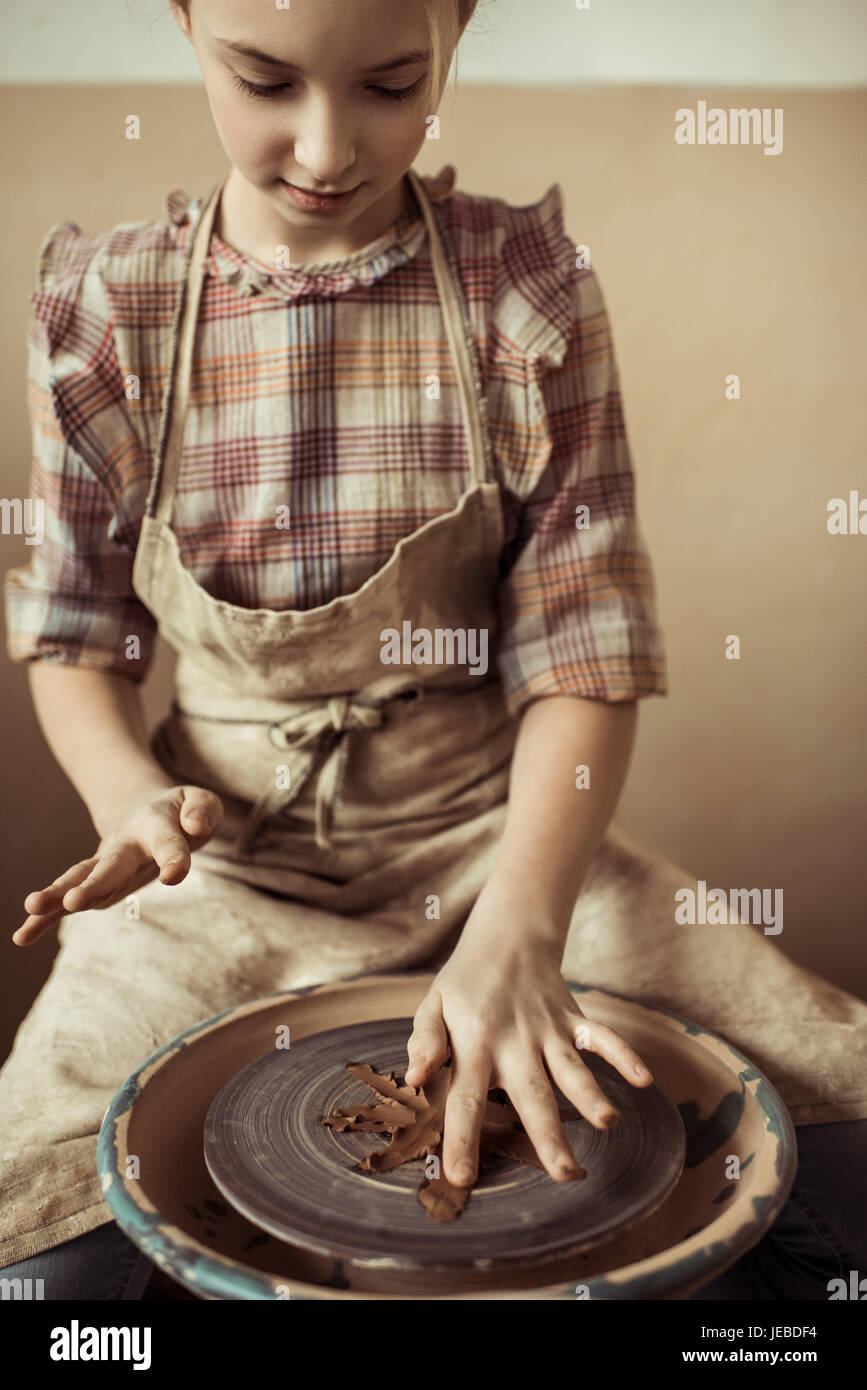 Front view of little girl making pottery on wheel at workshop Stock ...