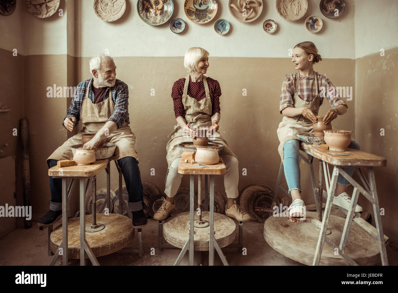Grandmother and grandfather with granddaughter making pottery at ...