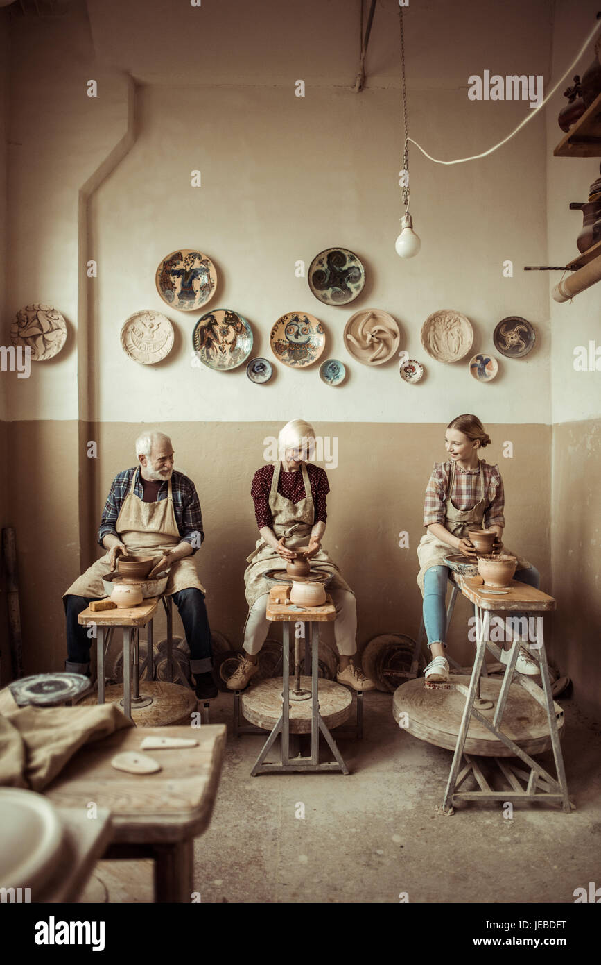Grandmother and grandfather with granddaughter making pottery at ...