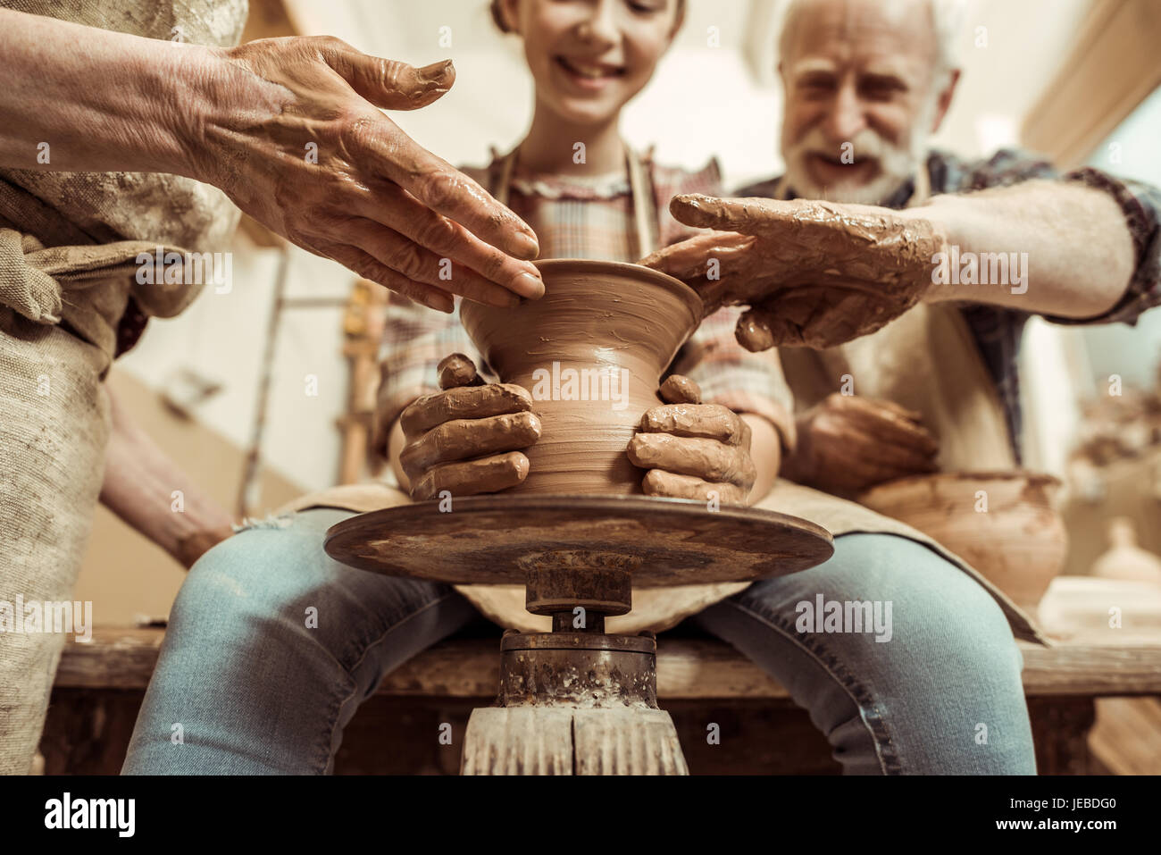 Grandmother and grandfather with granddaughter making pottery at ...