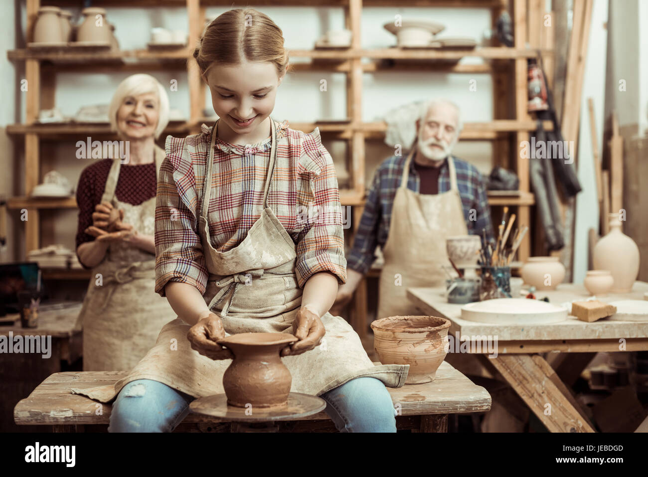 Grandmother and grandfather with granddaughter making pottery at ...