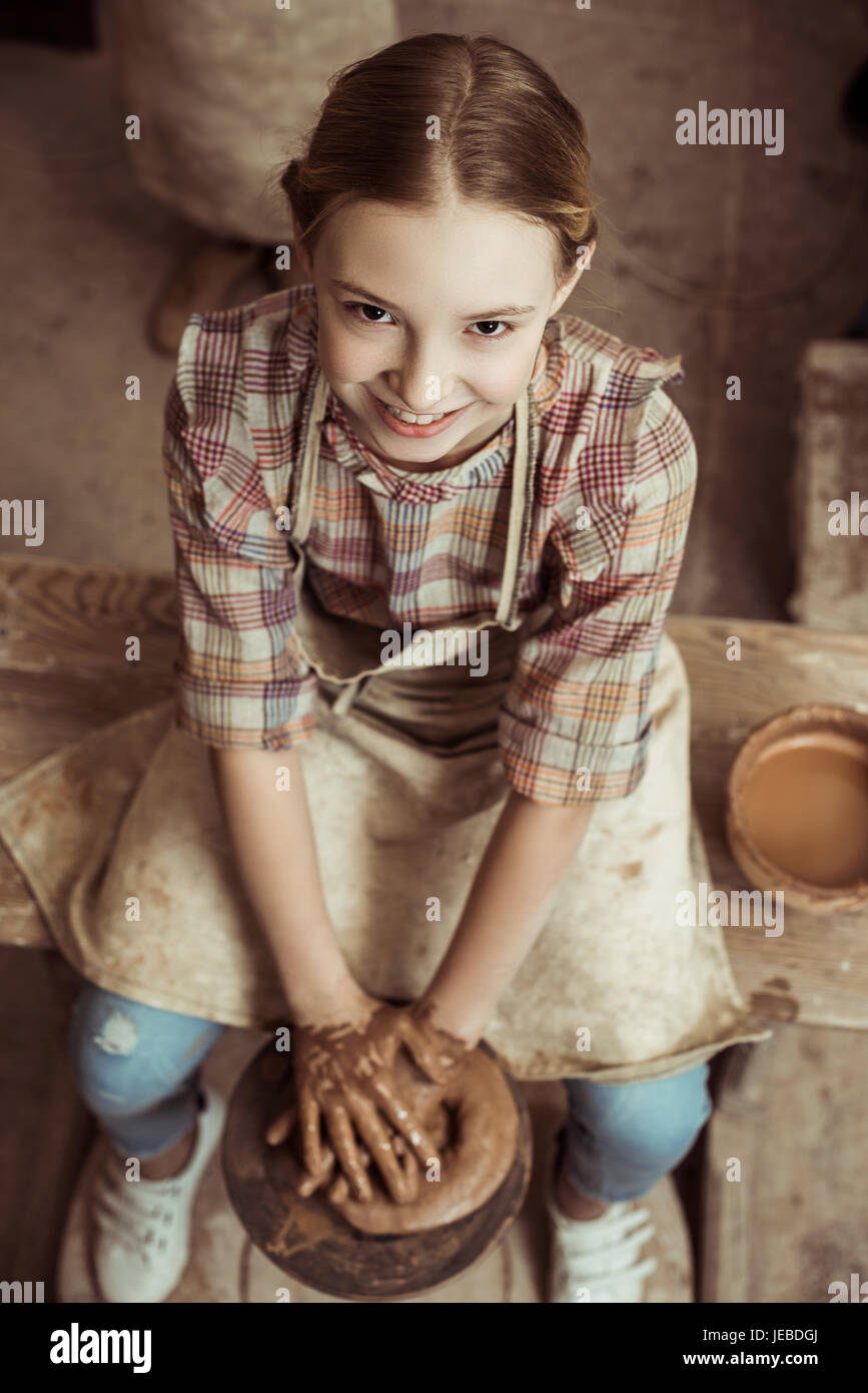 Overhead view of little girl making pottery on wheel at workshop Stock ...