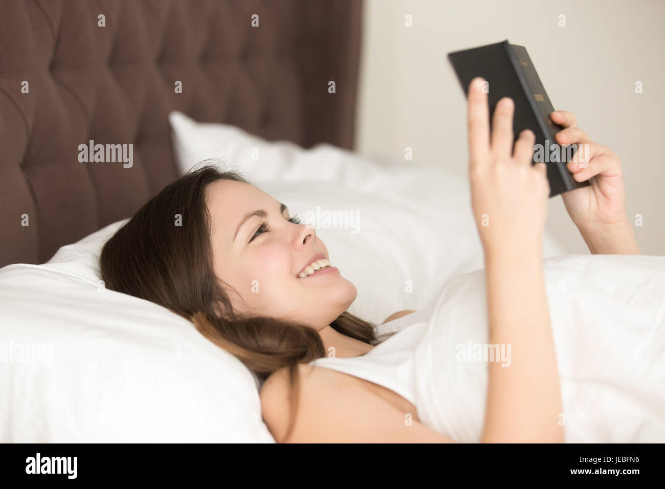 Happy lady in bed reading interesting book Stock Photo - Alamy