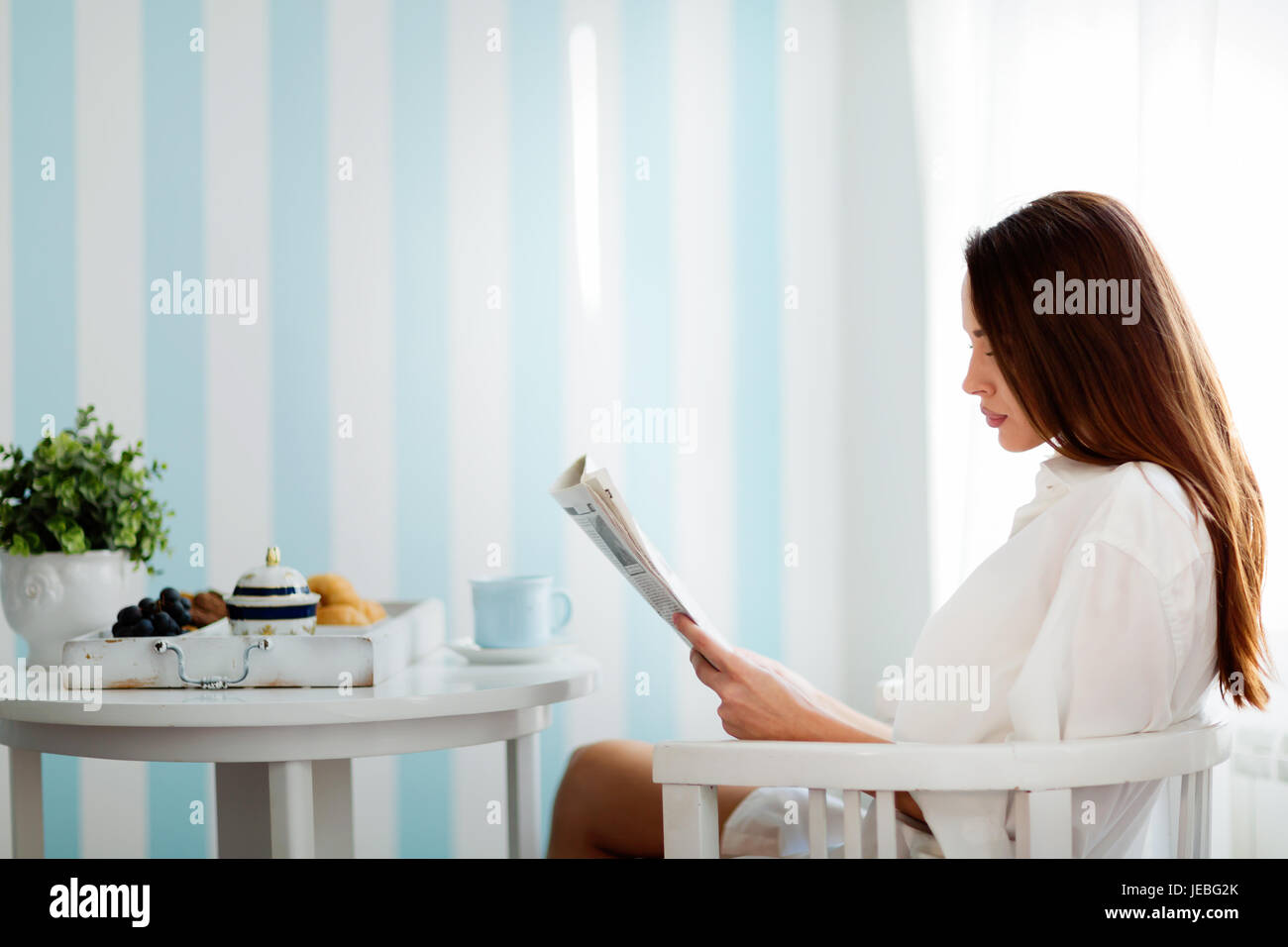 Peaceful young woman reading magazine at home Stock Photo - Alamy