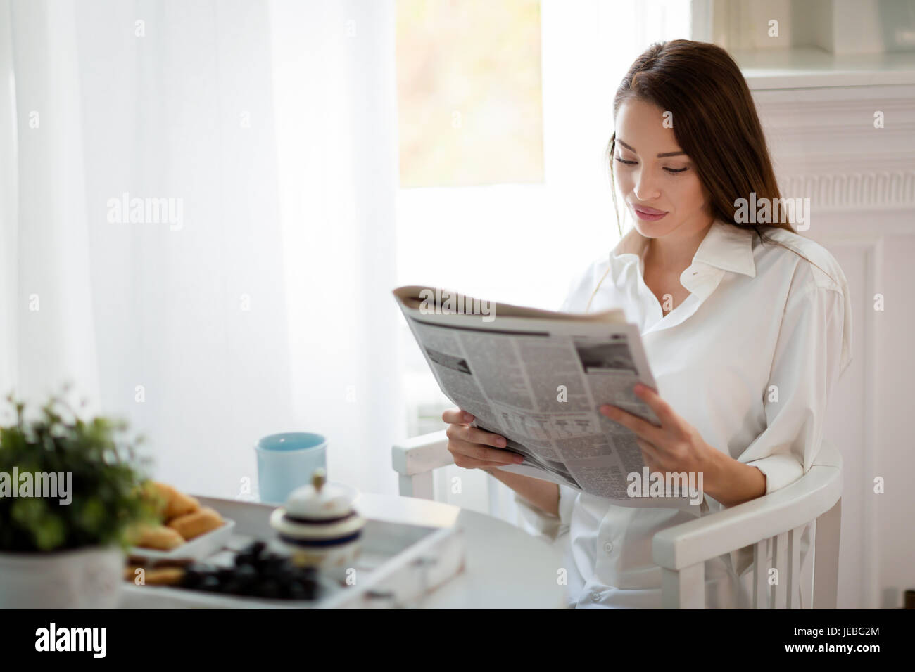 Young beautiful woman reading magazine at table Stock Photo - Alamy
