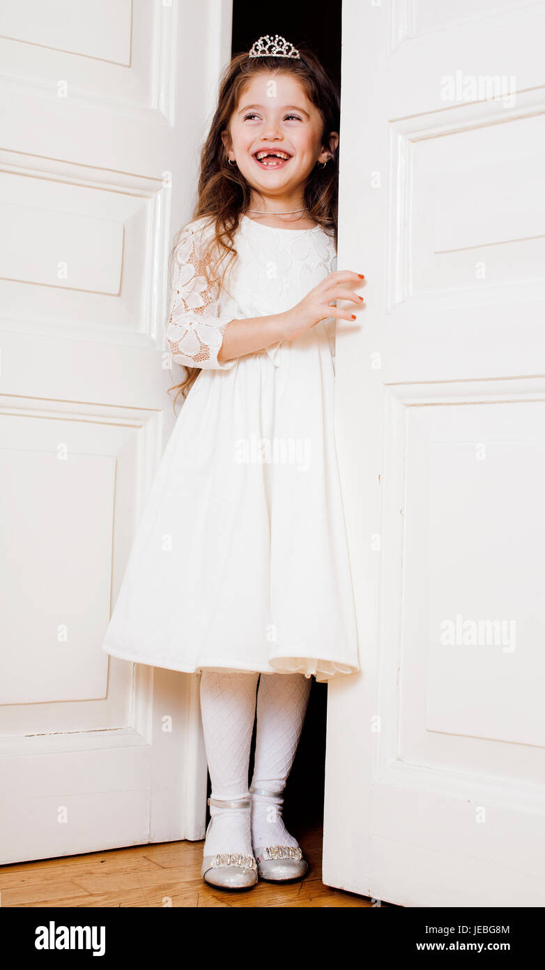 little cute girl at home, opening door well-dressed in white dress ...