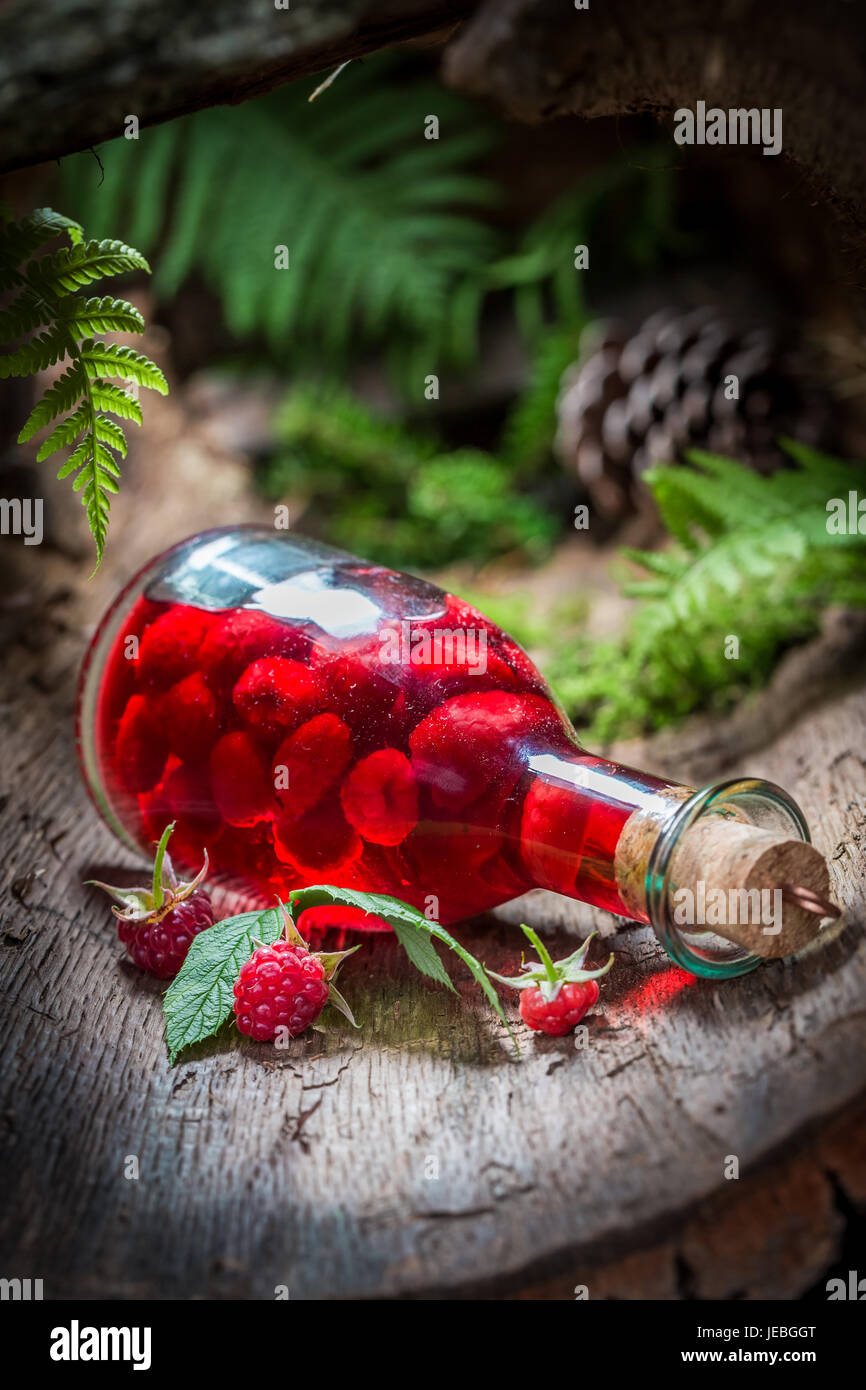 Raspberries liqueur made of alcohol and fruits in forest Stock Photo ...
