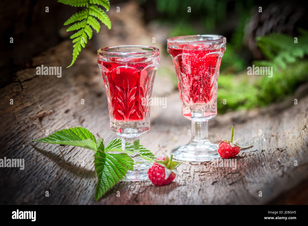 Delicious raspberries liqueur made of fruits and alcohol in forest ...