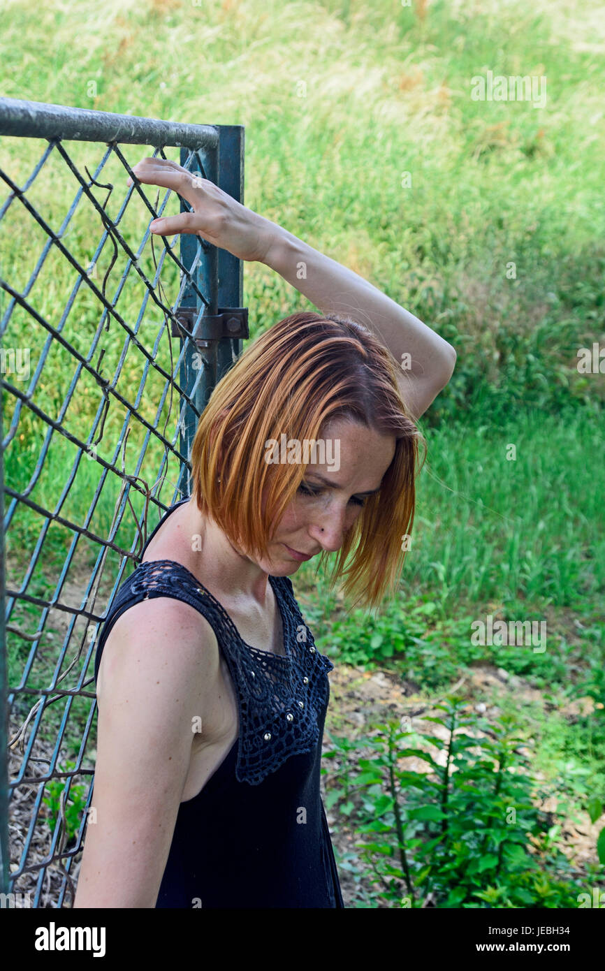 Girl posing behind an old iron gate. Since the fence is only gate ...
