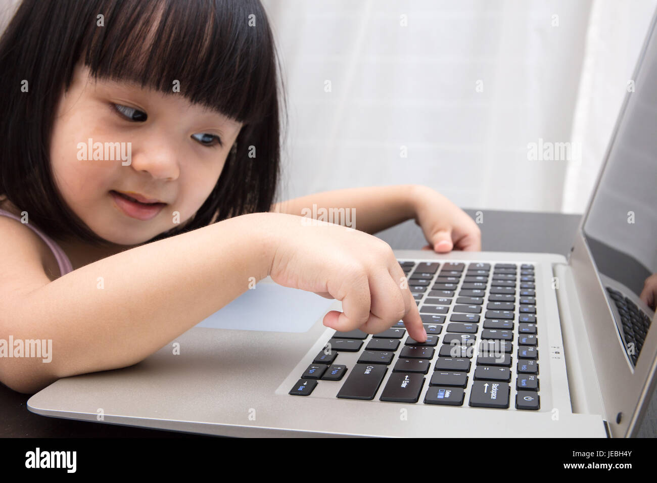 Smiling Asian Chinese little girl using laptop in the living room at ...