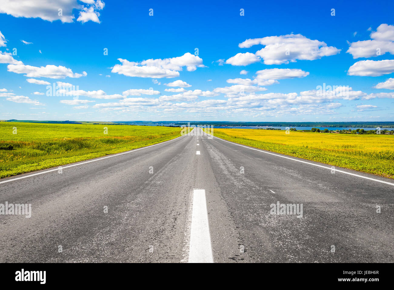 The road goes into the distance through the field on a background of a ...
