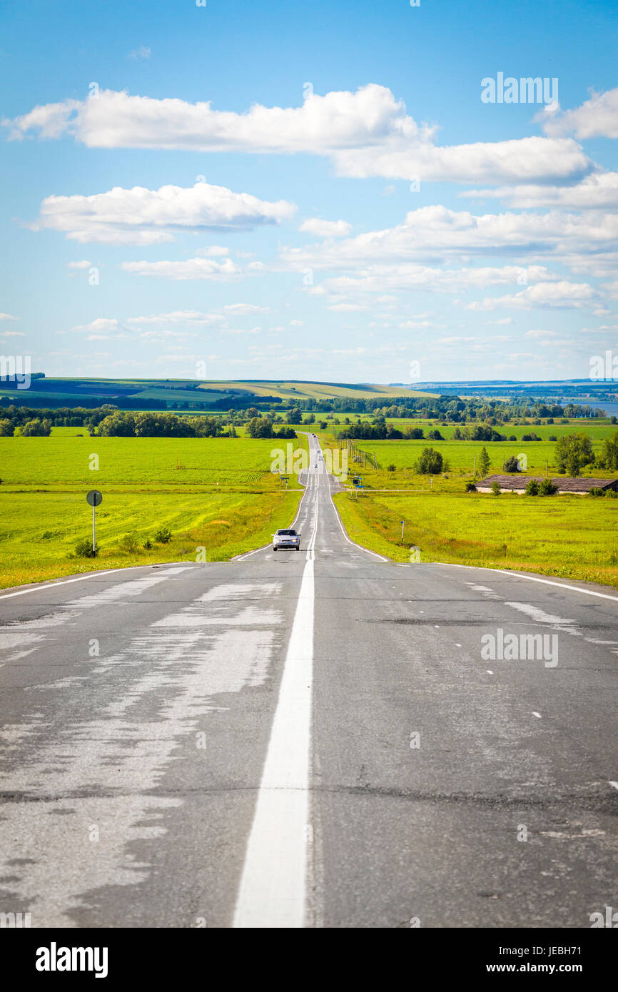 The road goes into the distance through the field on a background of a ...