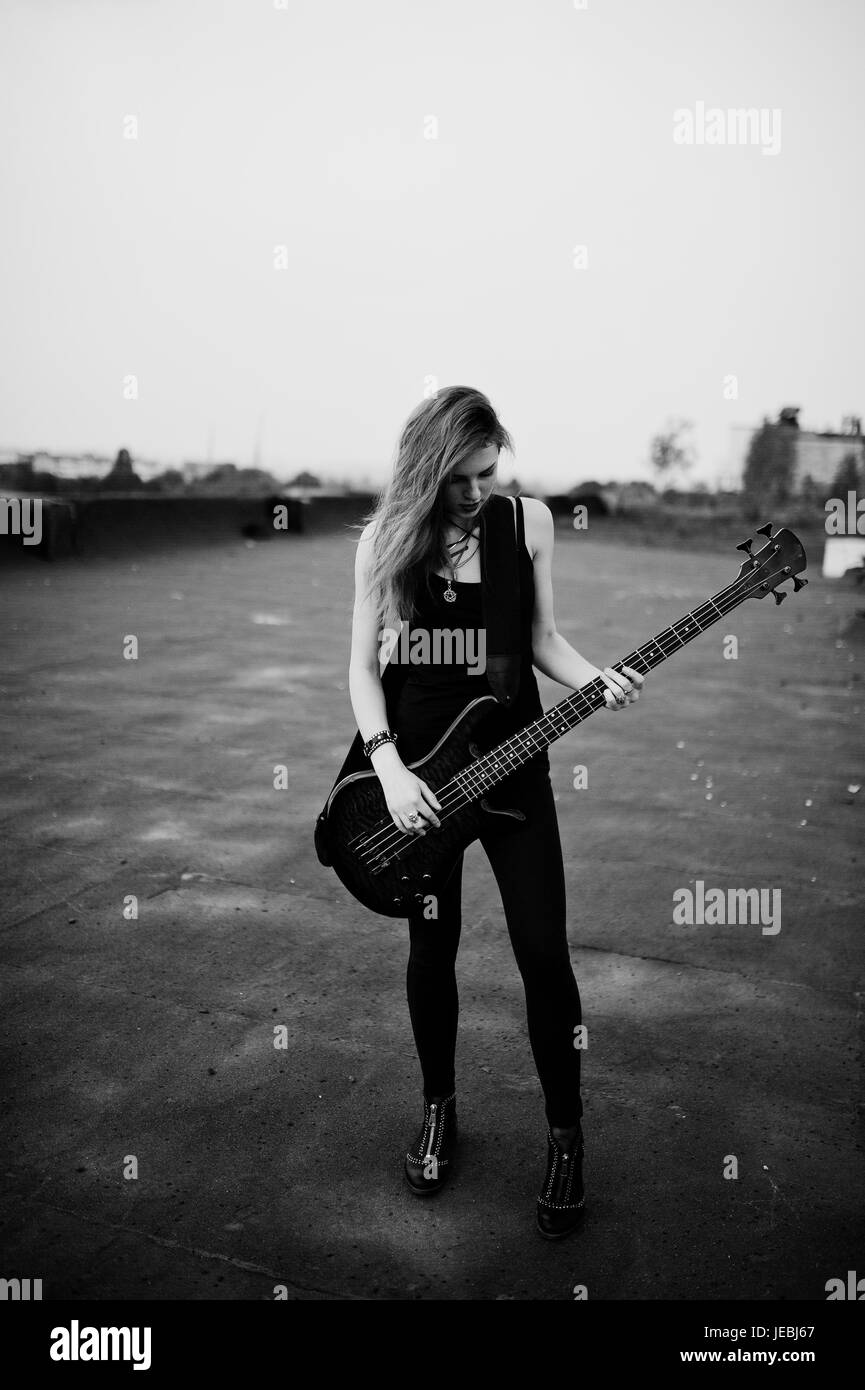 Red haired punk girl wear on black with bass guitar at the roof Stock ...