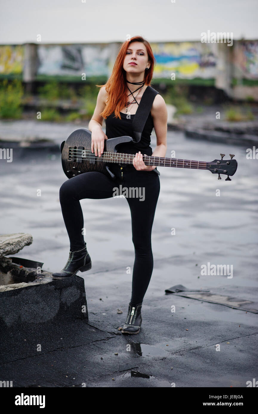 Red haired punk girl wear on black with bass guitar at the roof Stock ...