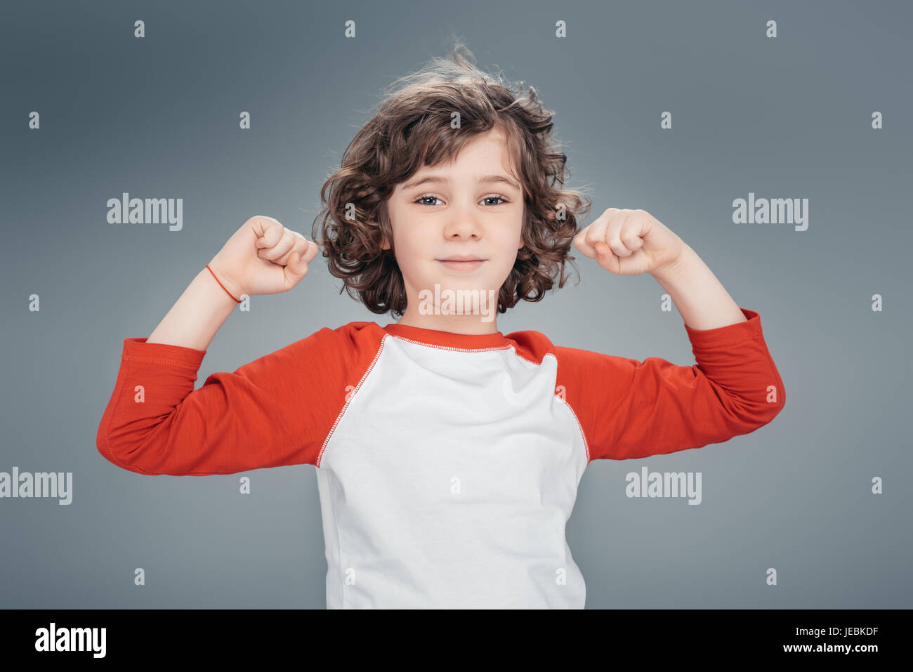 Little boy showing biceps isolated on gray background Stock Photo - Alamy
