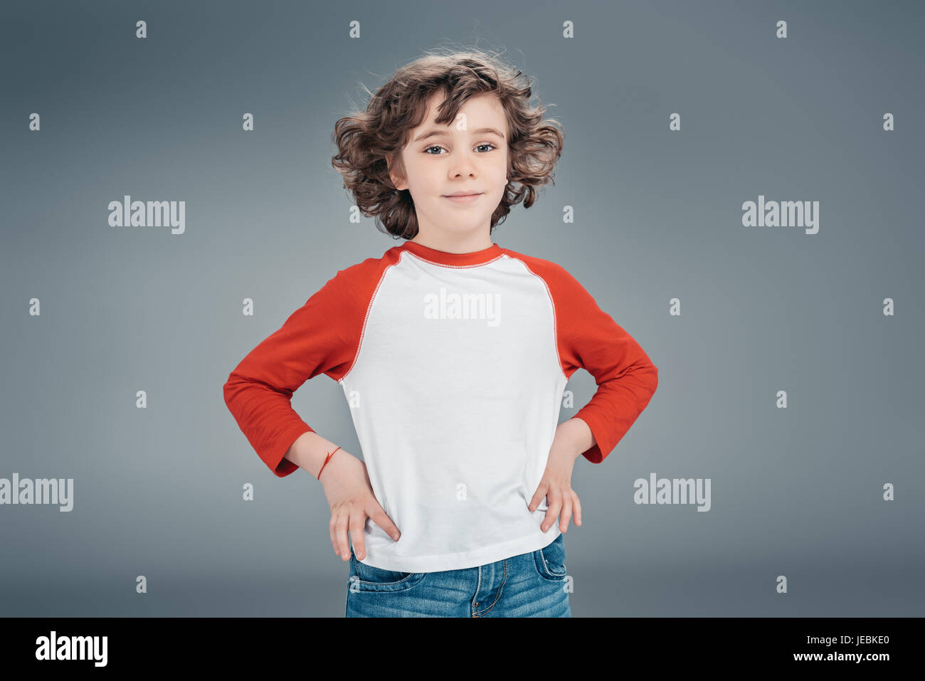 Pensive kid looking at camera and smiling isolated on gray Stock Photo ...