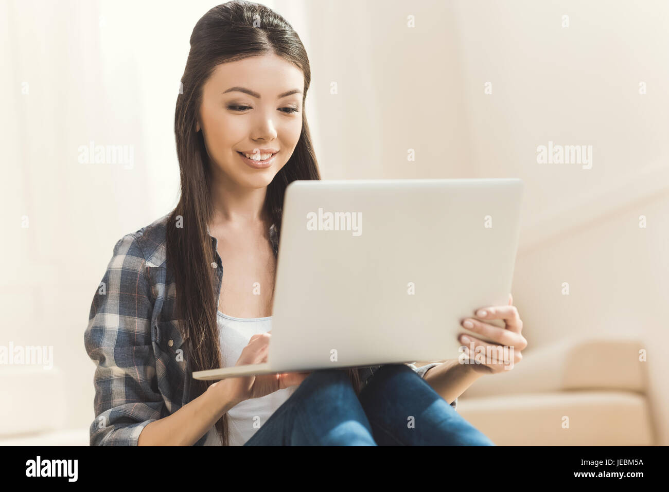 Front view of pretty woman sitting on floor and working on laptop ...
