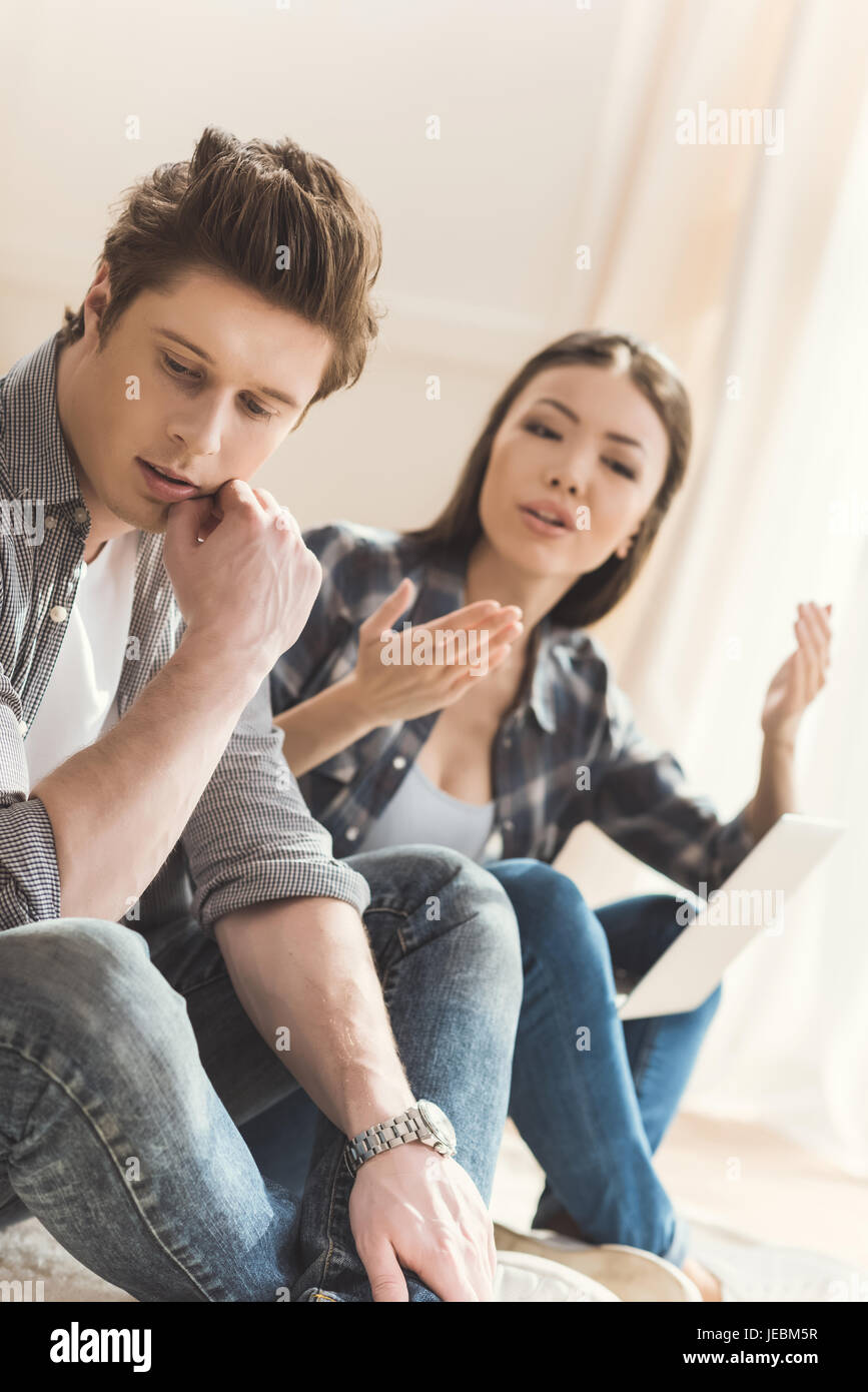 Beautiful couple arguing while sitting on floor at home Stock Photo - Alamy