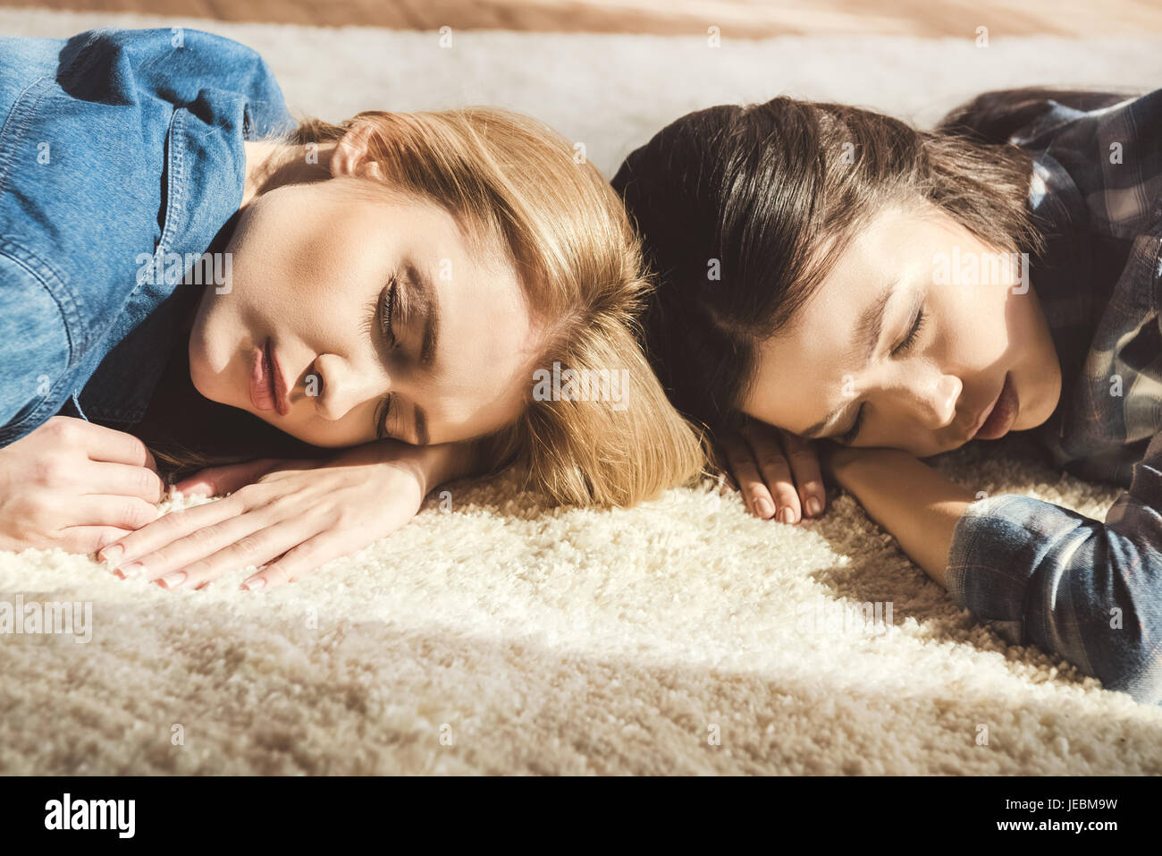 Two young women sleeping on carpet Stock Photo - Alamy