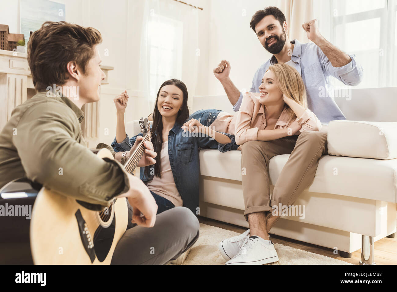 Diverse people partying together at dining room, playing acoustic ...