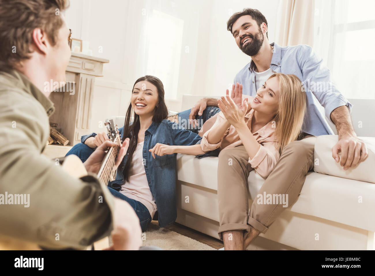 Diverse people partying together at dining room, playing acoustic ...