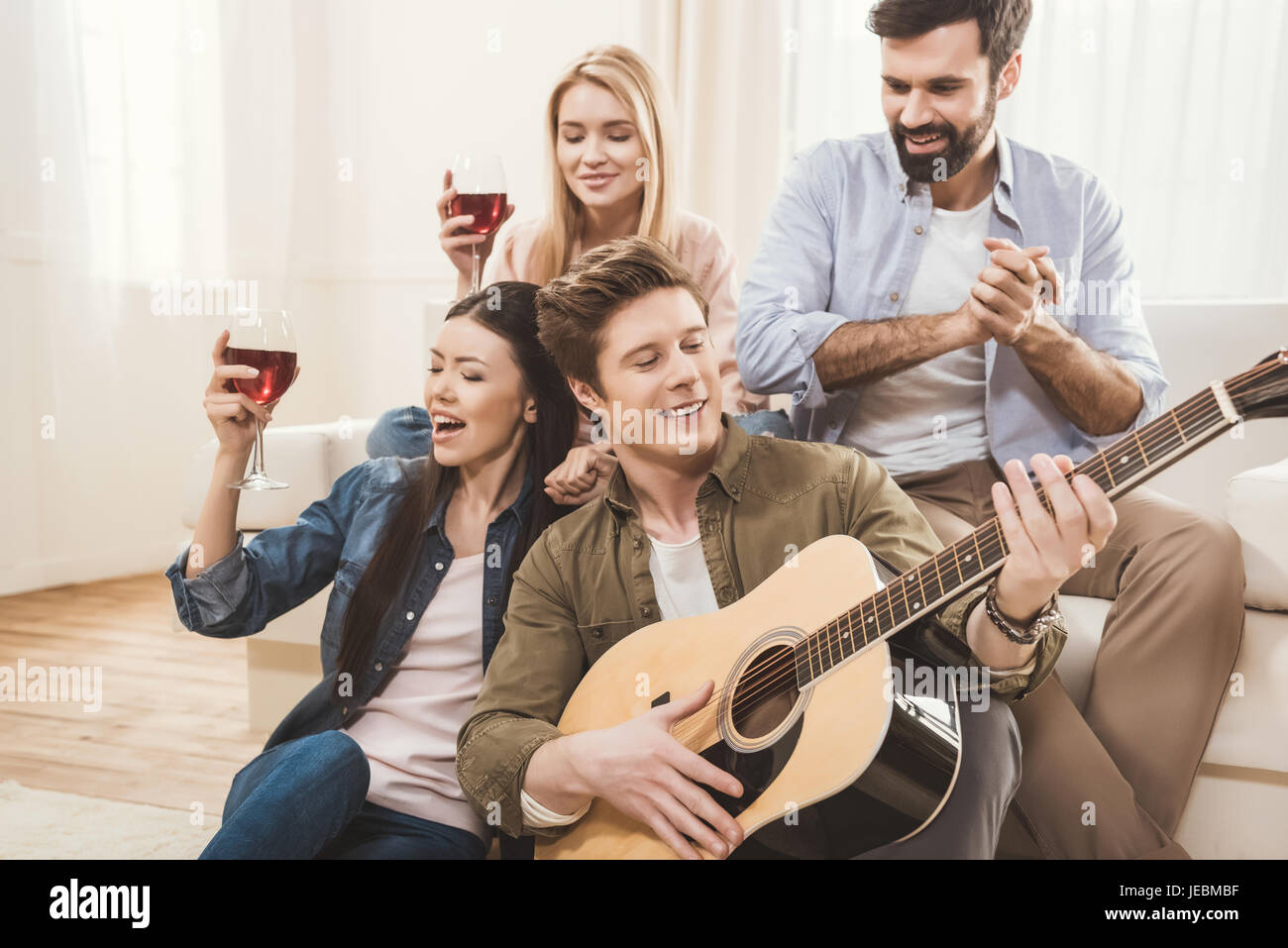 Diverse people partying together at dining room, playing acoustic ...