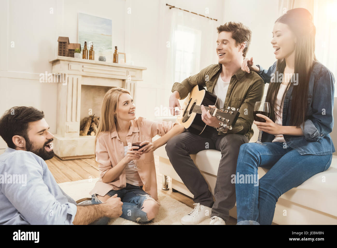 Diverse people partying together at dining room, playing acoustic ...