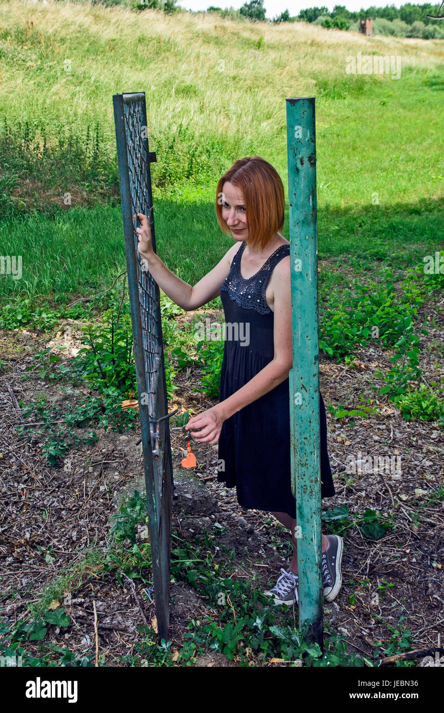Girl posing behind an old iron gate. Since the fence is only gate ...