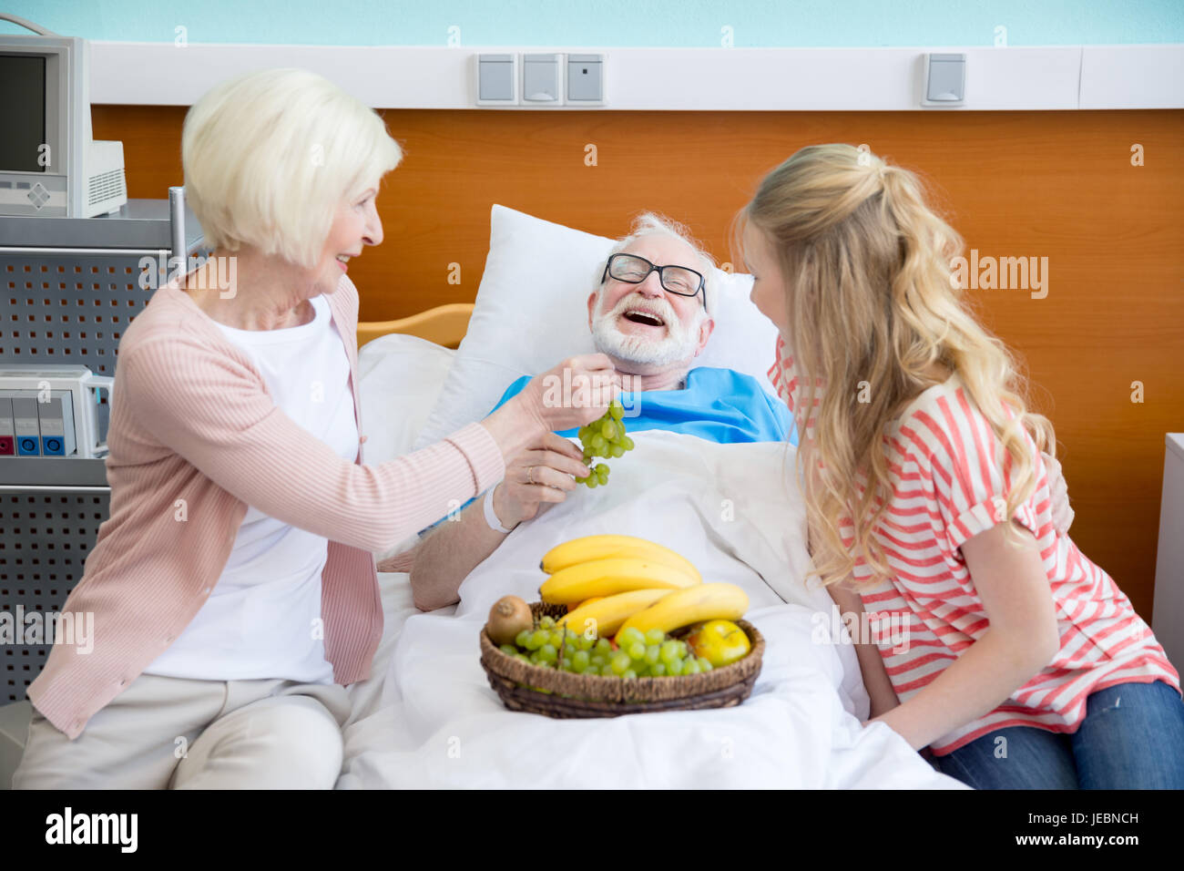 grandmother and granddaughter with fruits visiting patient in hospital ...