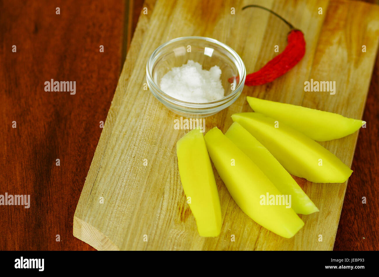 Close up shot of sliced mango served with salt and a red chilli pepper ...