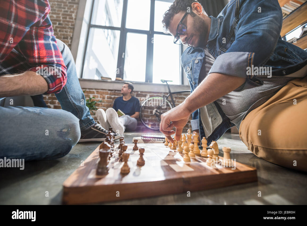 young men sitting on floor and playing chess on chess board Stock Photo ...