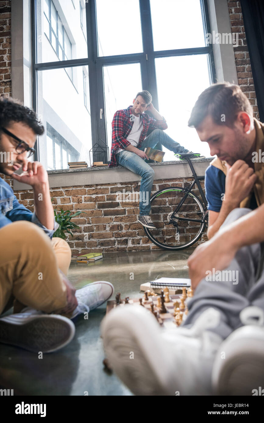 young men sitting on floor and playing chess on chess board Stock Photo ...