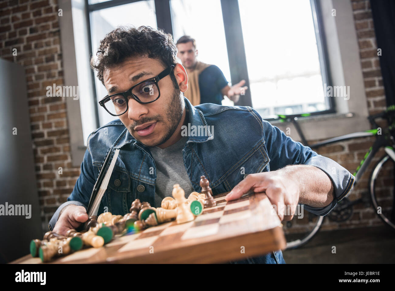 scared man holding chess board with friend behind Stock Photo - Alamy