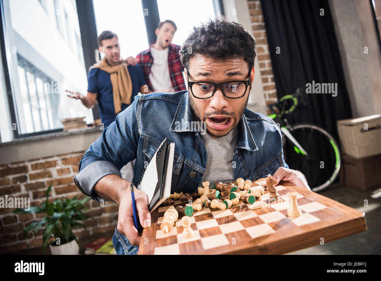 scared man holding chess board with friends behind Stock Photo - Alamy