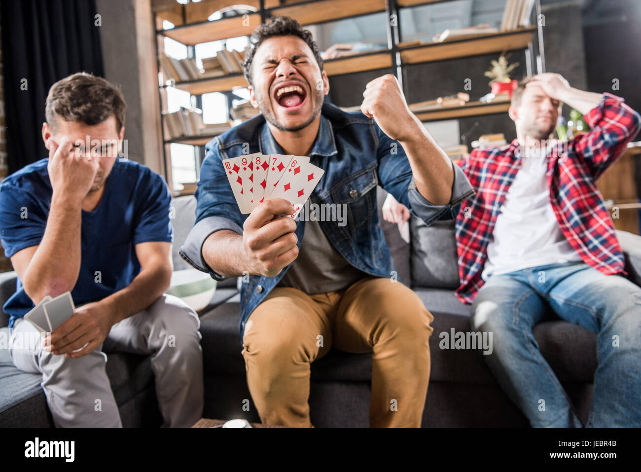 Triumphing young man sitting on sofa and showing street flash of ...