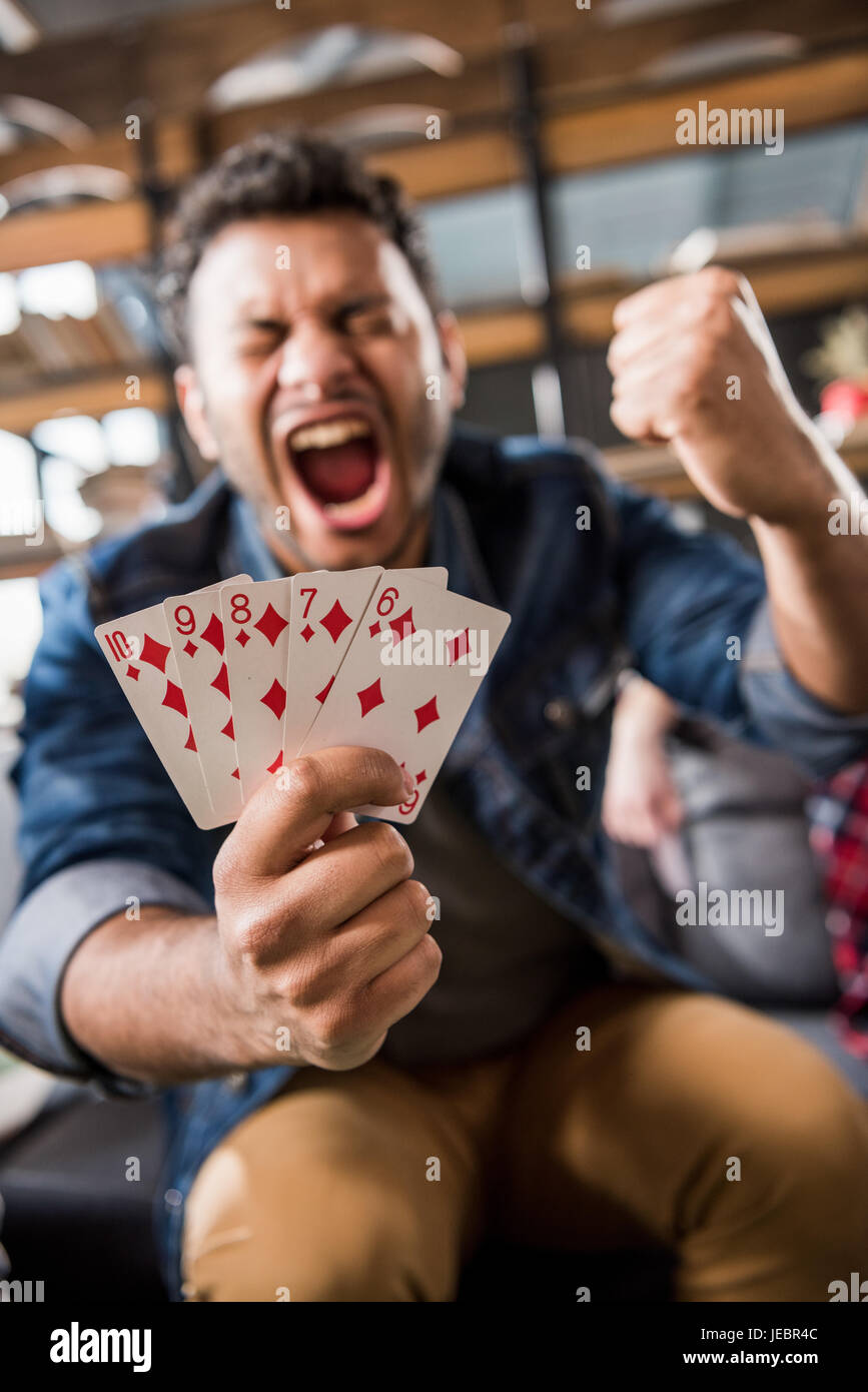 Triumphing young man sitting on sofa and showing street flash of ...