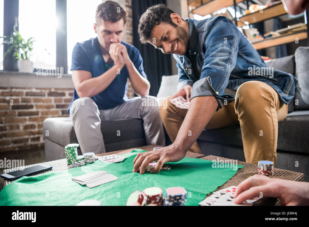 Young men playing cards at gaming table, young people having fun ...