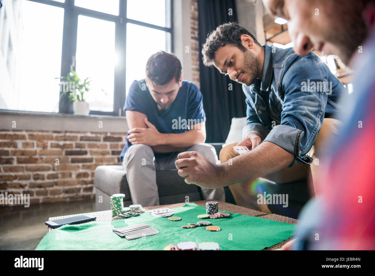 Young men playing cards at gaming table, young people having fun ...