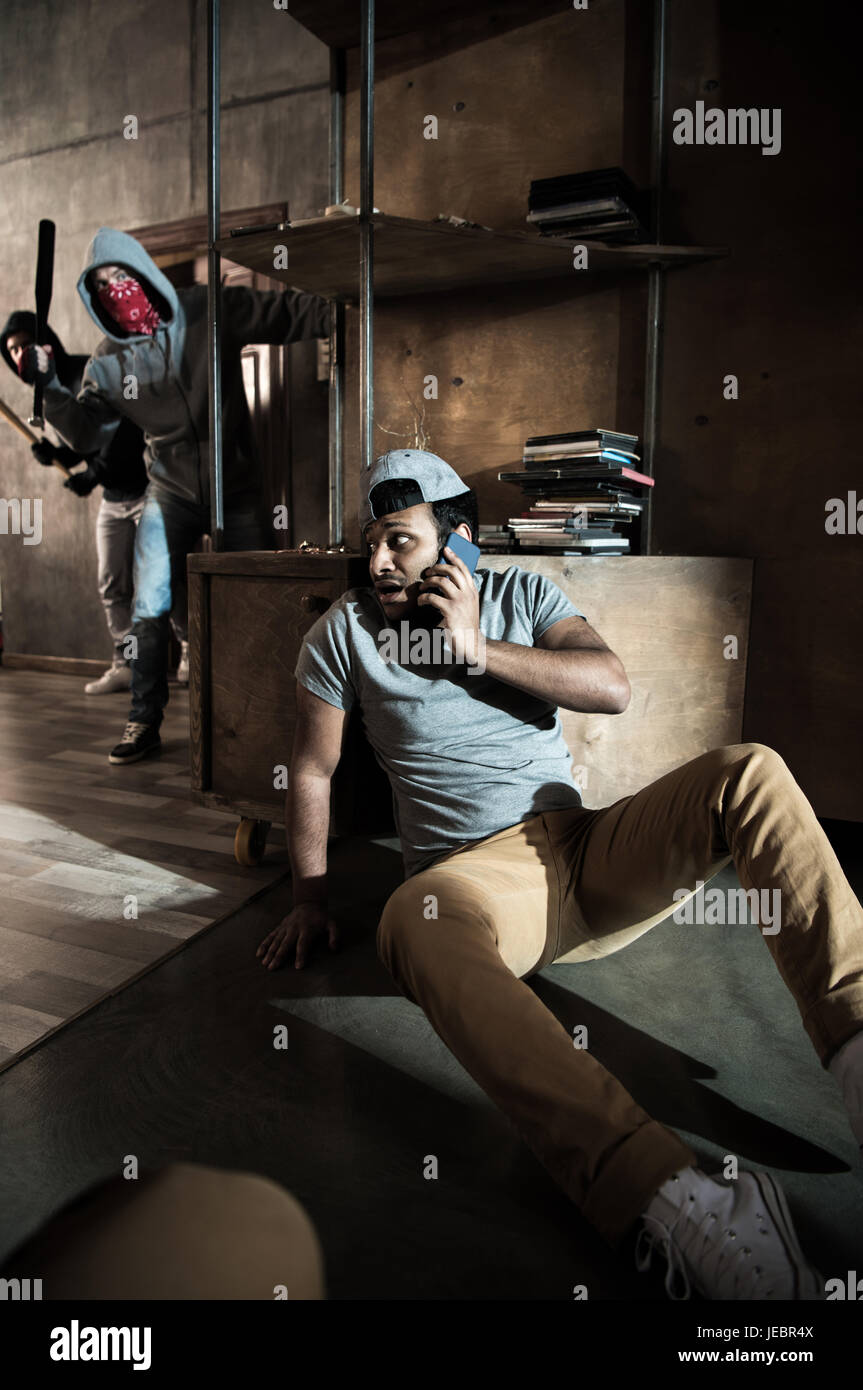 Scared man hiding from burglars breaking indoors, house robbery scene ...