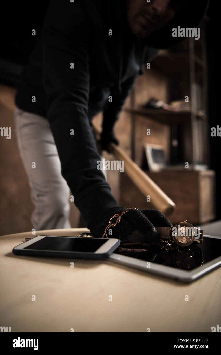 Close-up partial view of robber stealing valuables, house robbery scene ...