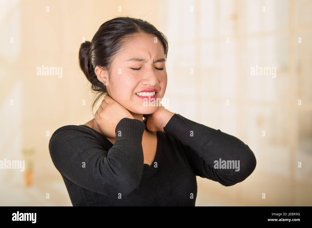 Young hispanic woman posing for camera showing signs of neck pain ...